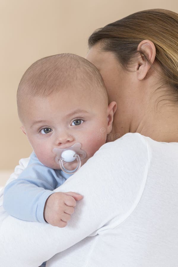Young Mother Holding a Baby with Pacifier in Her Arms Stock Image ...