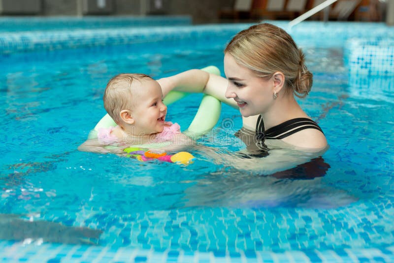 Young Mother, Swimming Instructor and Happy Little Girl in the Pool ... Young Mother, Swimming Instructor and Happy Little Girl in the Pool ...