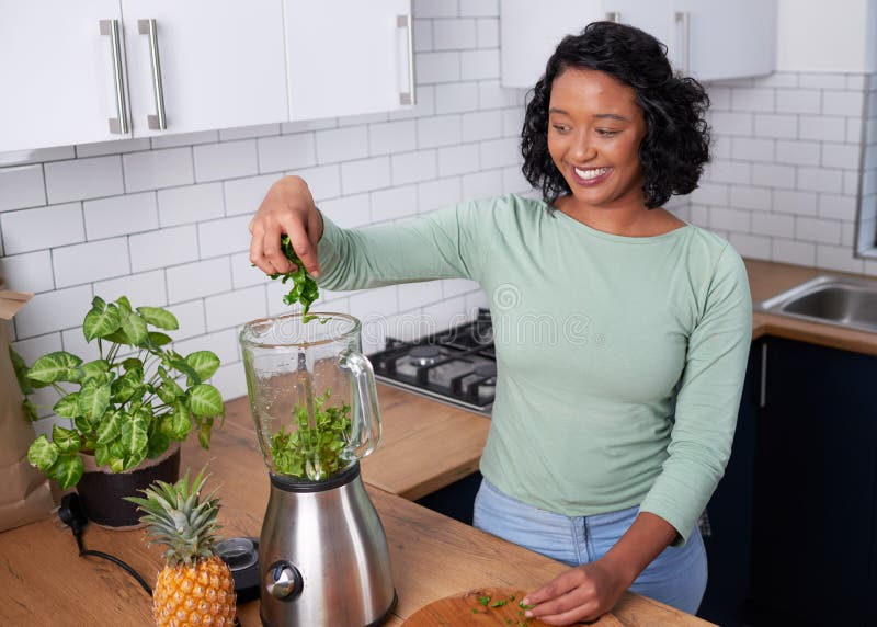 A Young Multi Ethnic Woman Puts Chopped Spinach Into A Blender To Make