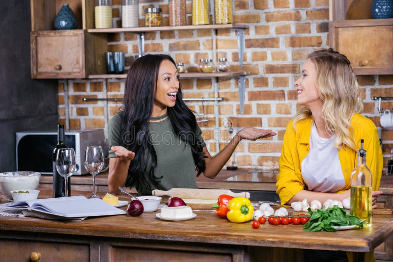 Young Multiethnic Women Cooking Together and Talking in Kitchen Stock ...