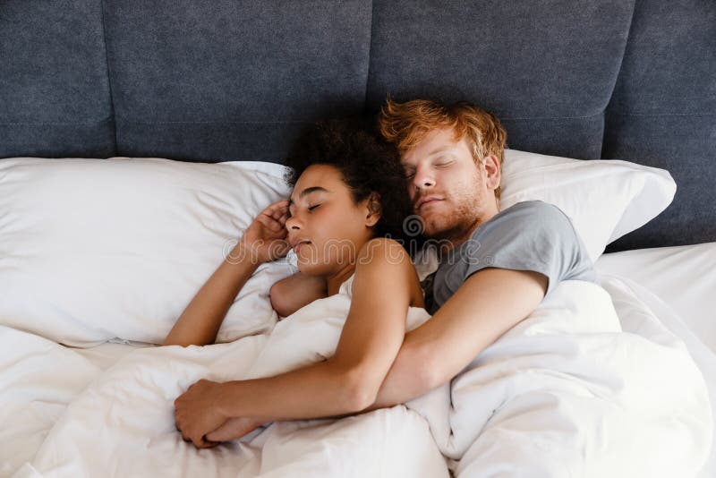 Young Multinational Couple Hugging while Sleeping Together at Home ...