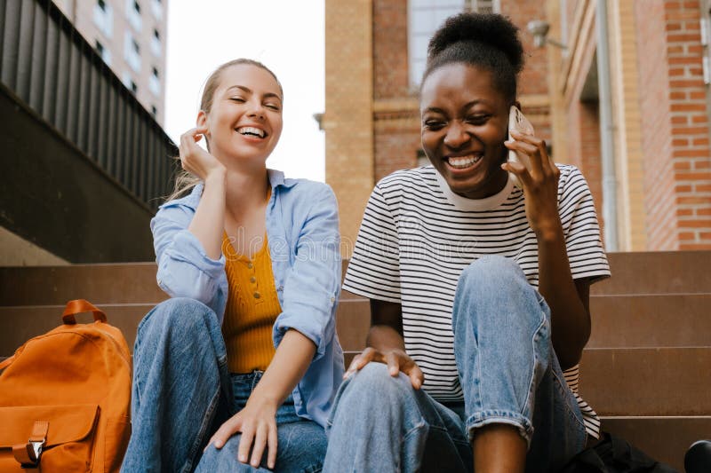 Young Multinational Girls Laughing and Using Cellphone Together Stock ...