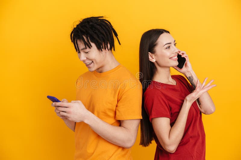 Young Multiracial Couple Smiling while Using and Talking on Cellphones ...