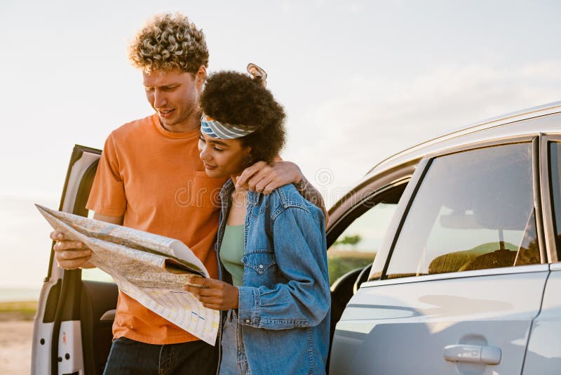 Young Multiracial Couple Talking and Examining Map during Car Trip ...