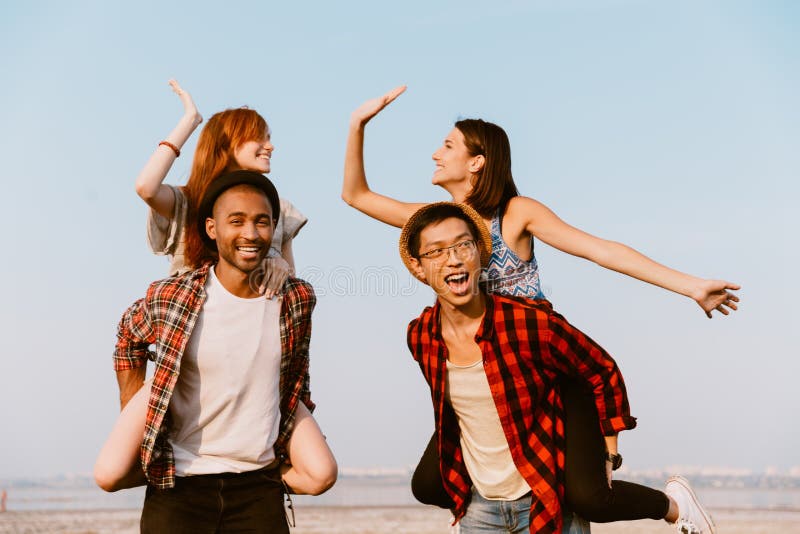 Young Multiracial Couples Giving High Five and Piggybacking Together ...