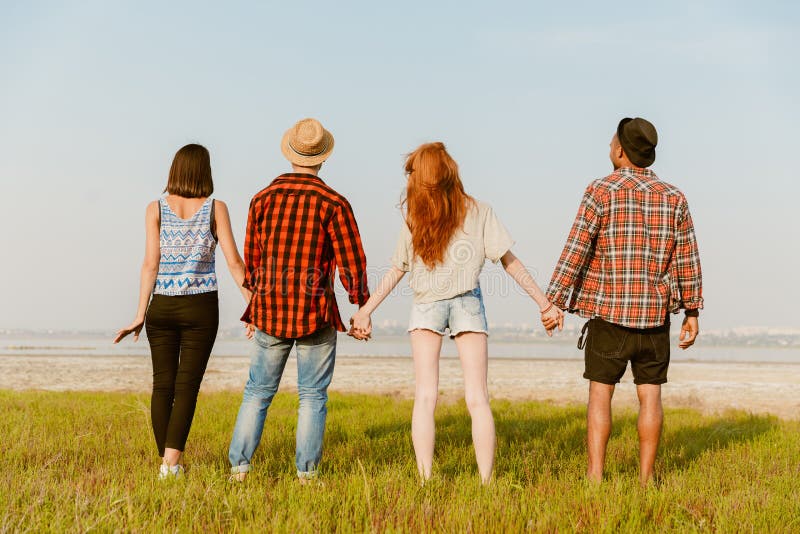 Young Multiracial Friends Holding Hands while Standing Back at Camera ...