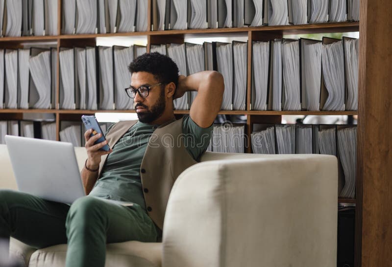 Young Multiracial Man Sitting on Sofa and Working. Stock Photo - Image ...