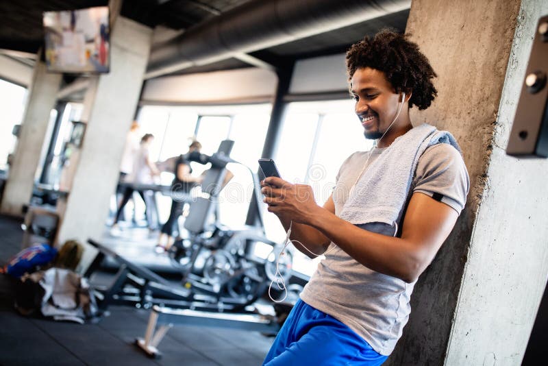 Young Muscular Man Using Mobile Phone at the Gym in Exercise Break ...