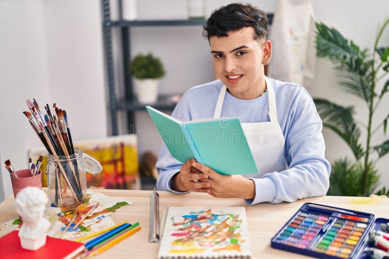 Young Non Binary Man Artist Smiling Confident Reading Book at Art ...