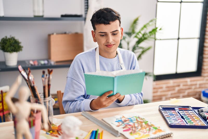 Young Non Binary Man Artist Smiling Confident Reading Book at Art ...