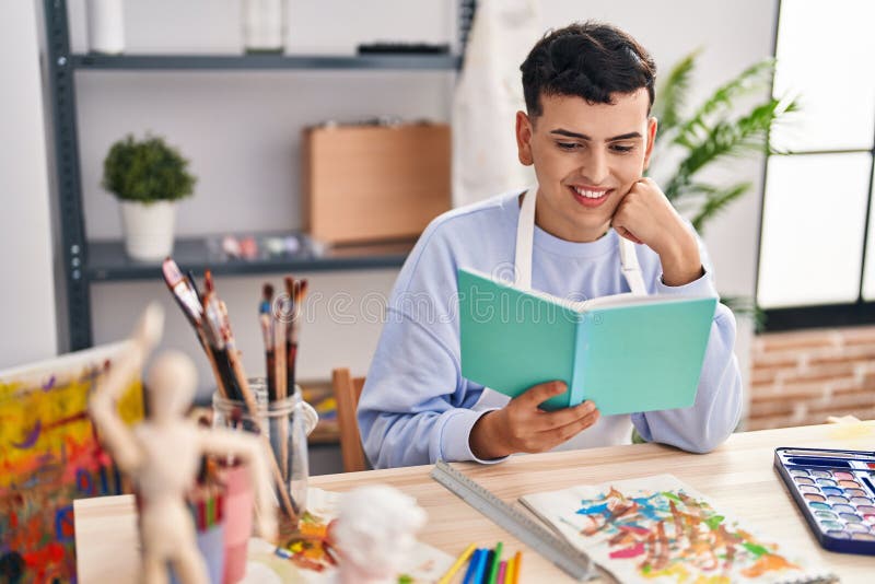 Young Non Binary Man Artist Smiling Confident Reading Book at Art ...