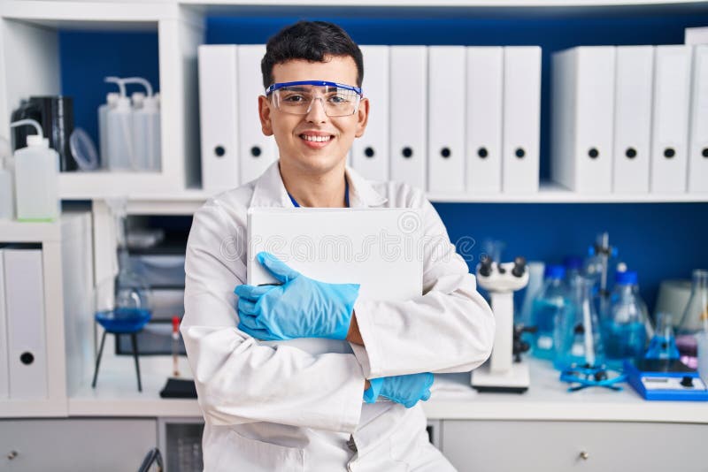 Young Non Binary Man Scientist Smiling Confident Hugging Binder at ...
