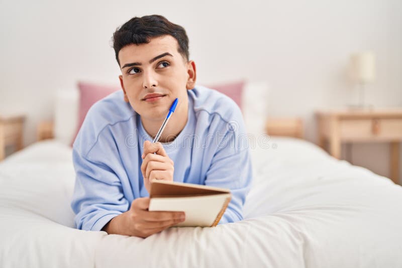 Young Non Binary Man Writing on Notebook Lying on Bed Stock Image ...