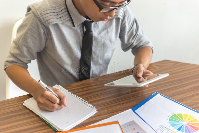 Young Office Man Using Tablet and Writing into Note Stock Image - Image ...