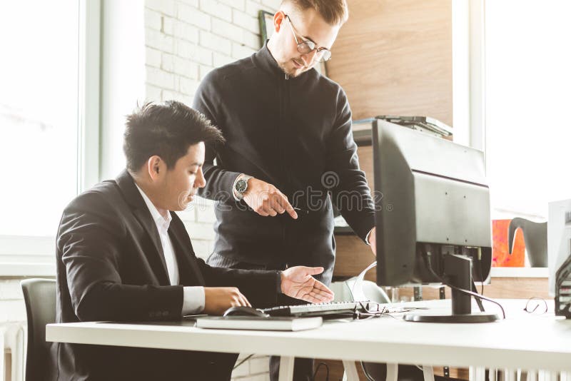 Young Office Worker Sitting at Desk, Using Computer. Two Business Man ...