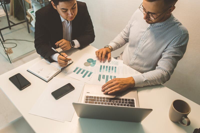 Young Office Worker Sitting at Desk, Using Computer. Two Business Man ...