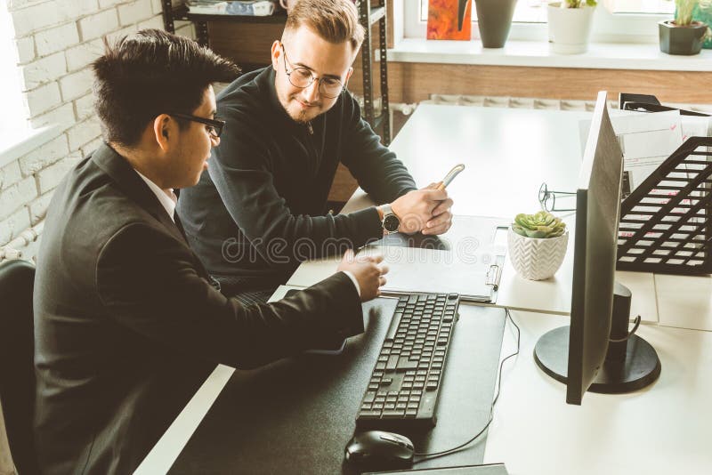 Young Office Worker Sitting at Desk, Using Computer. Two Business Man ...