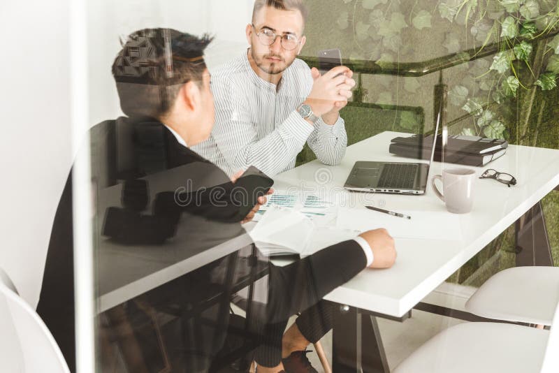 Young Office Worker Sitting at Desk, Using Computer. Two Business Man ...