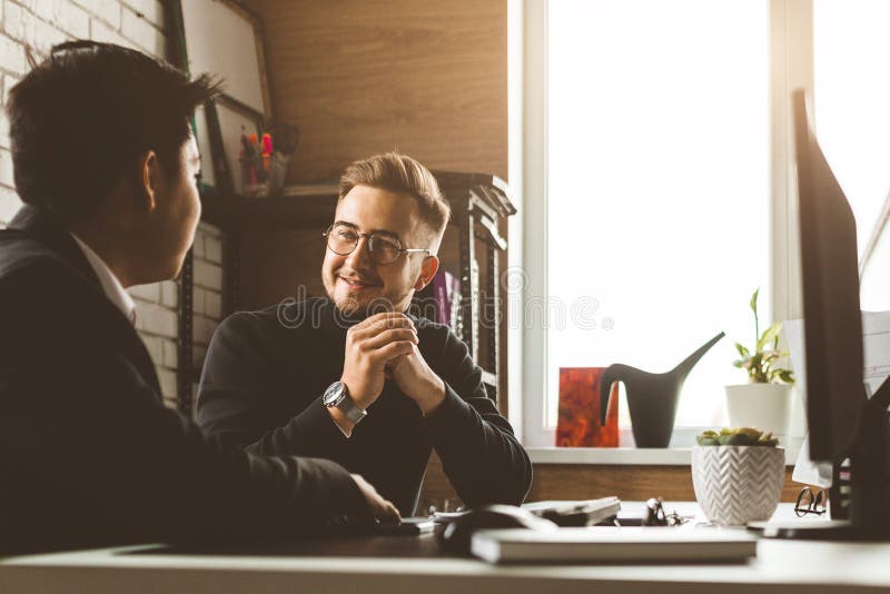 Young Office Worker Sitting at Desk, Using Computer. Two Business Man ...
