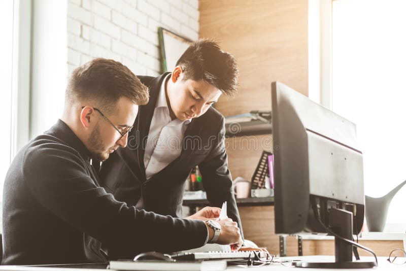 Young Office Worker Sitting at Desk, Using Computer. Two Business Man ...