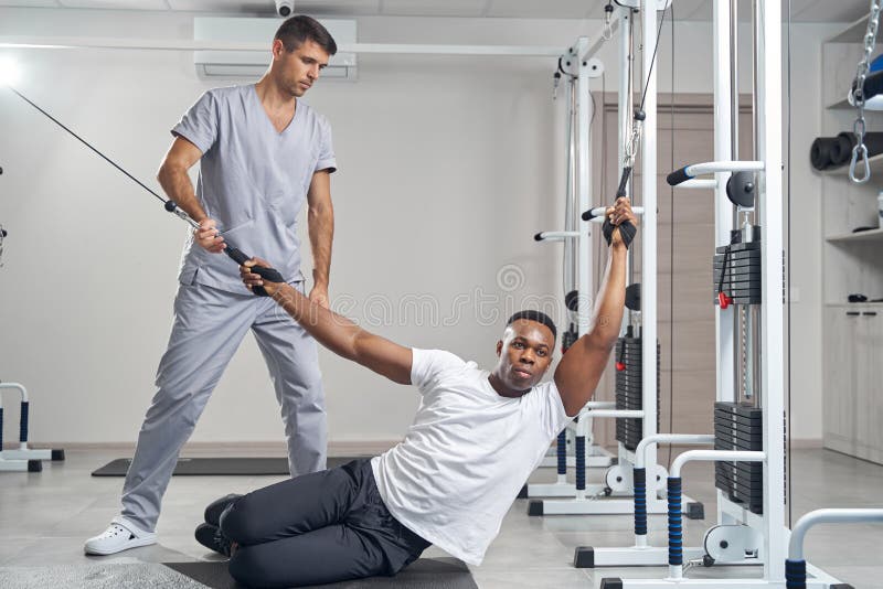 Young Patient Performing Stretching Exercise Using Cable Machine Stock ...