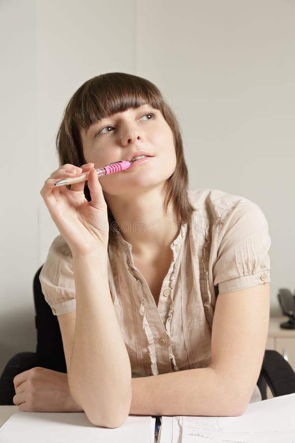 Young Pensive Woman Biting Pen Stock Photo - Image of pretty, desk ...