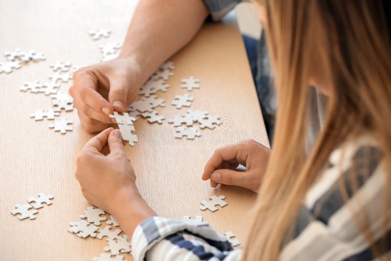 Young People Assembling Puzzle on Wooden Table Stock Image - Image of ...