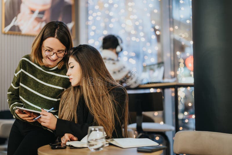 Two Young Women Engaged in a Collaborative Work Session at a Cafe, with ...