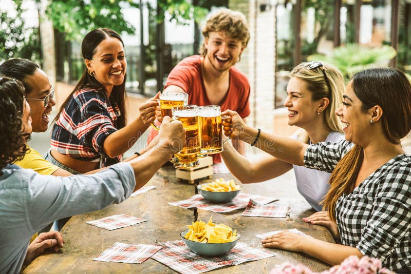 Group Of Friends Cheering Beer Glasses In Brewery Pub Garden Stock