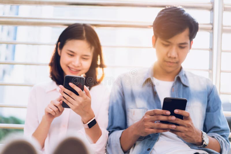 Young People are Using Smartphone and Smiling while Sitting on Free ...