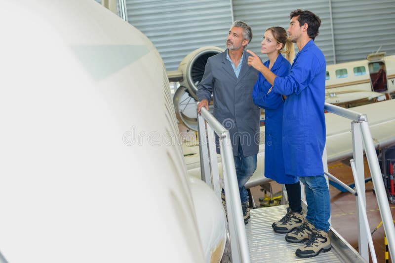 People in Aircraft Hangar Looking at Manual Stock Image - Image of ...