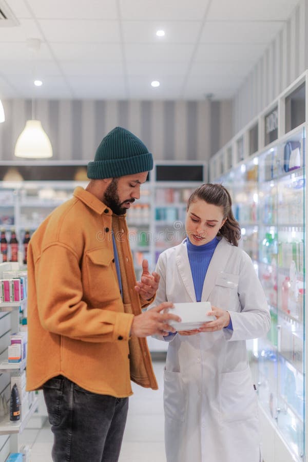 Young Pharmacist Helping Customer To Choos Medication. Stock Photo ...