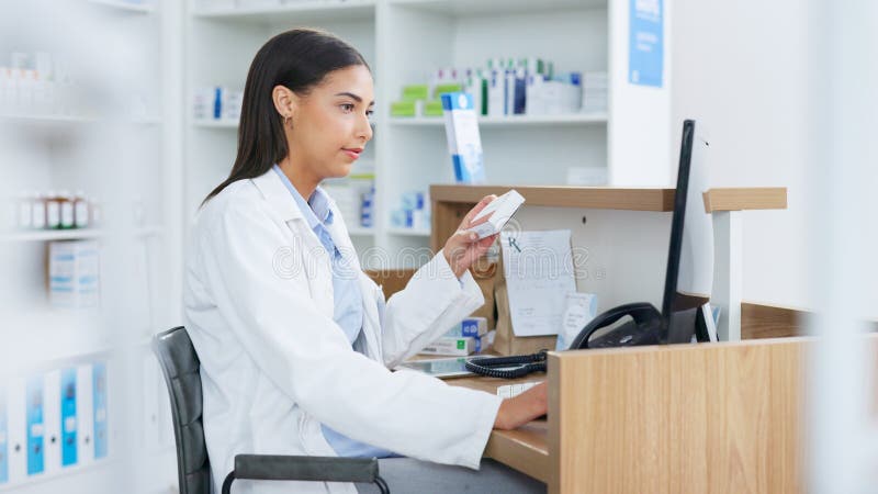 Young Pharmacist Working on Computer at a Pharmacy Counter. Woman Using ...