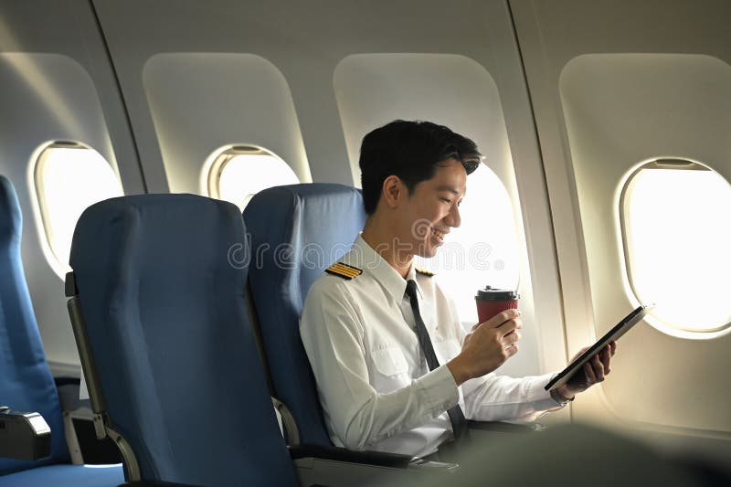 Young Pilot Drinking Coffee and Reading Document on an Airplane ...