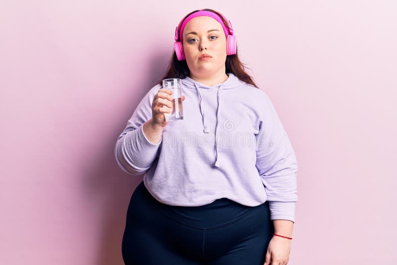 Young Plus Size Woman Drinking Glass of Water Using Headphones Thinking ...