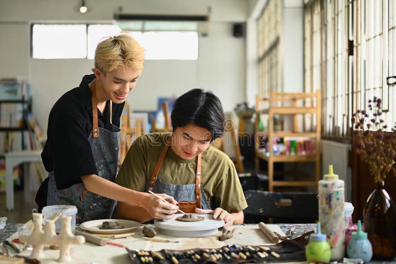 Young Potter Helping Student Shaping and Scraping Raw Clay in the ...