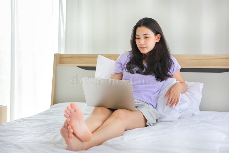Young Pretty Girl Working from Home on Her Bed Using Computer Laptop To ...