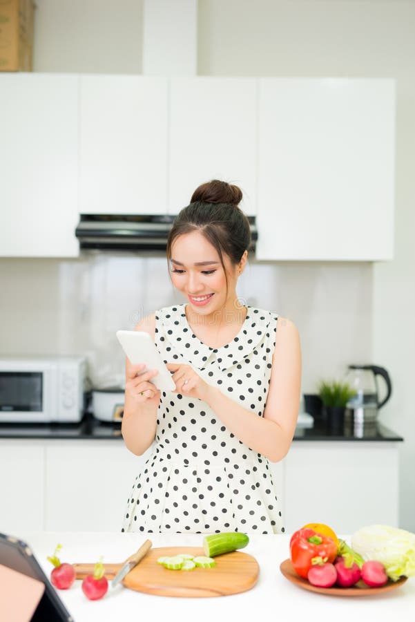 Young Pretty Woman Using Smart Phone while Cooking in Kitchen Stock ...