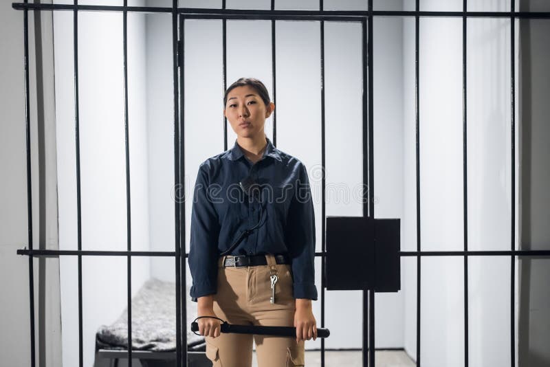 A Young Prison Guard Poses in Front of Prison Bars in Uniform. in a ...