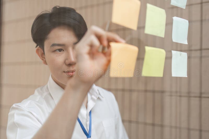 Young Professional Arranging Sticky Notes on Glass Wall, Organizing ...