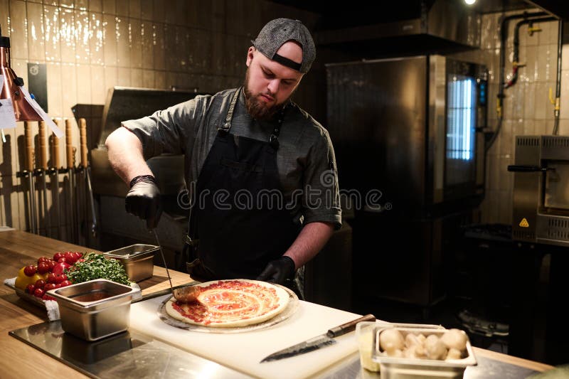 Young Professional Chef in Uniform Spreading Ingredients on Pizza ...