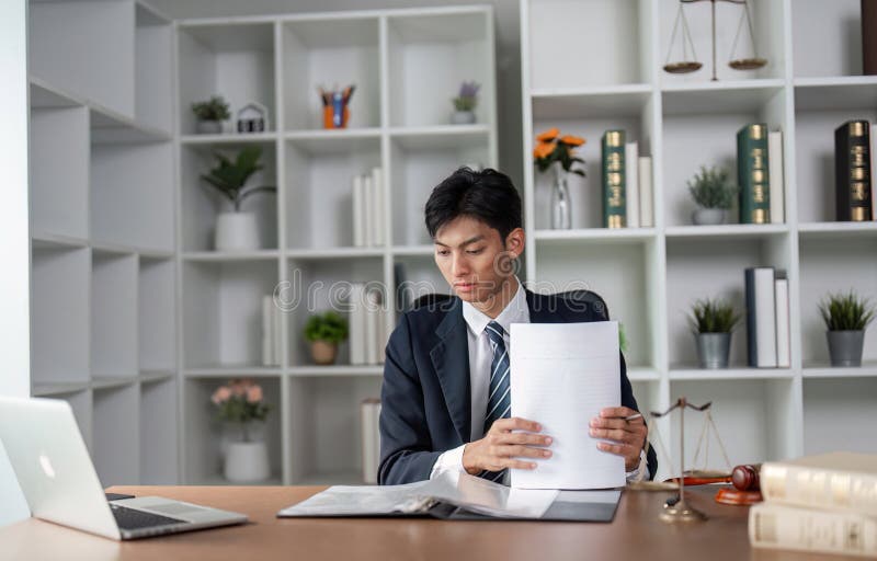 Young Professional in Suit Examining Documents at Desk, Focused on ...