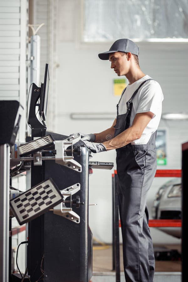 A Young and Qualified Mechanic is Working on Details at a Car Service ...