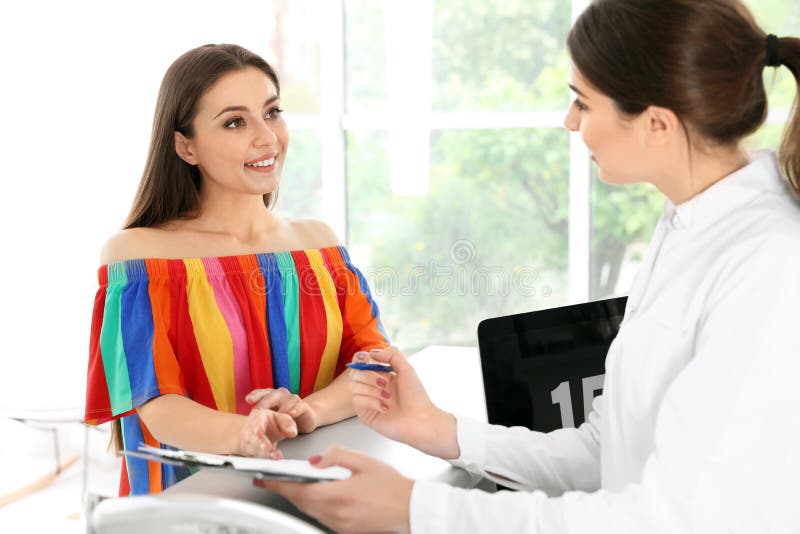 Young Receptionist Working with Client at Desk Stock Image - Image of ...