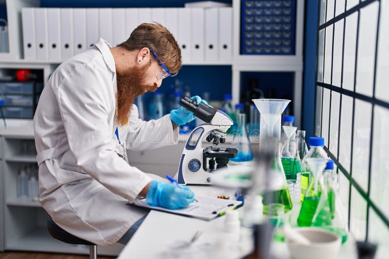 Young Redhead Man Scientist Using Microscope Writing Report Working at ...