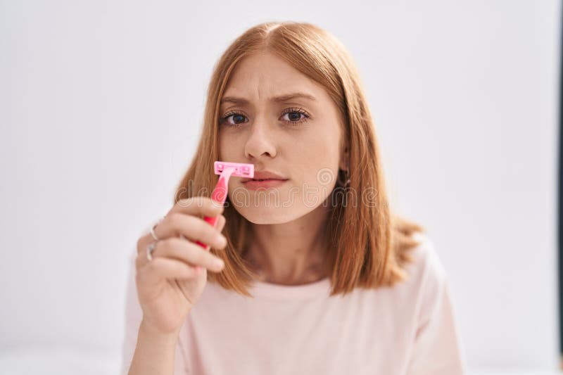 Young Redhead Woman Using Razor on Moustache at Bedroom Stock Photo ...