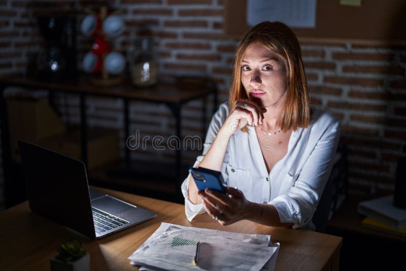 Young Redhead Woman Working at the Office at Night Serious Face ...
