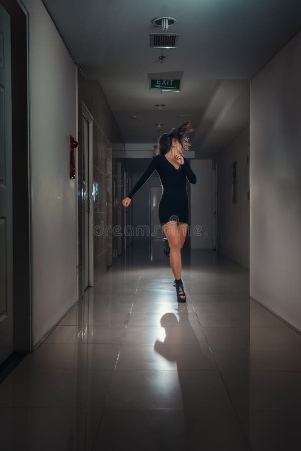 A Young Scared Woman in a Panic Runs Away Along a Dark Corridor Stock ...