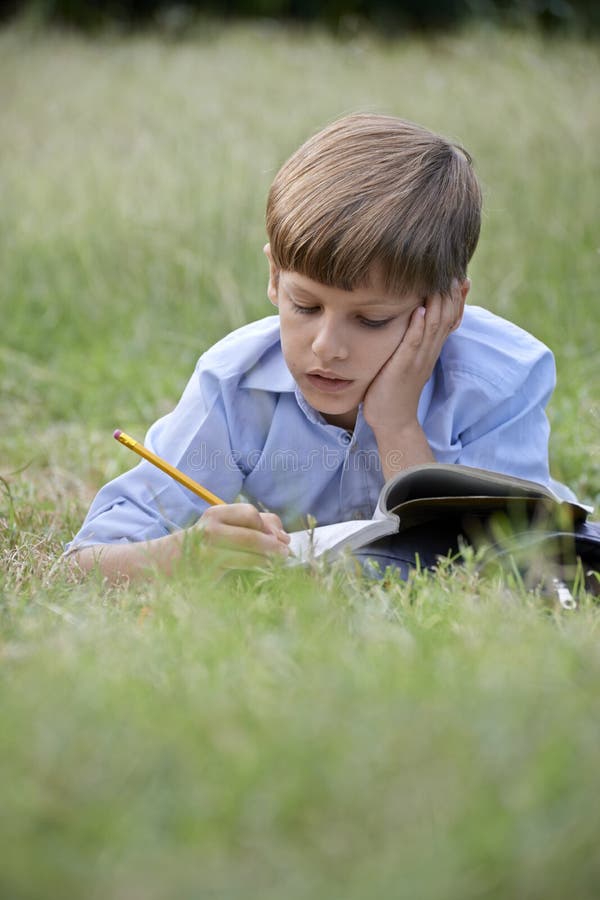 Young School Boy Doing Homework Alone, Lying on Grass Stock Image ...