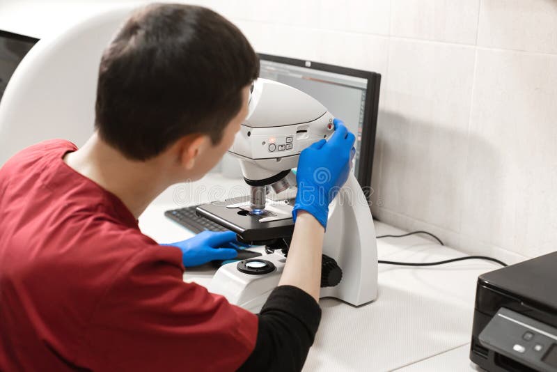 Young Scientist Looking through a Microscope in a Laboratory. Young ...